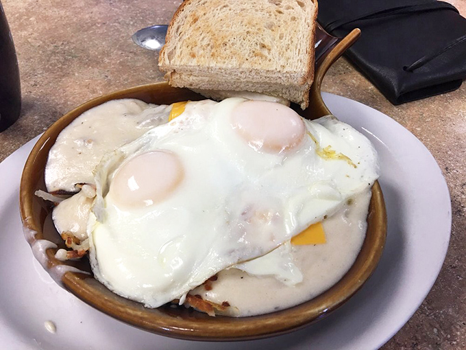 Two sunny-side up eggs rest atop what appears to be hash browns—a simple pleasure that somehow tastes better when someone else makes it.
