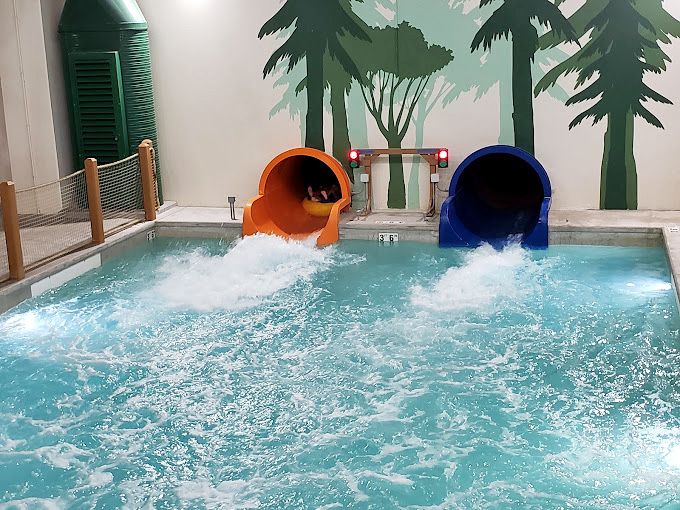 Orange and blue water slides emptying into a splash pool – like colorful straws delivering pure joy directly to your vacation experience.