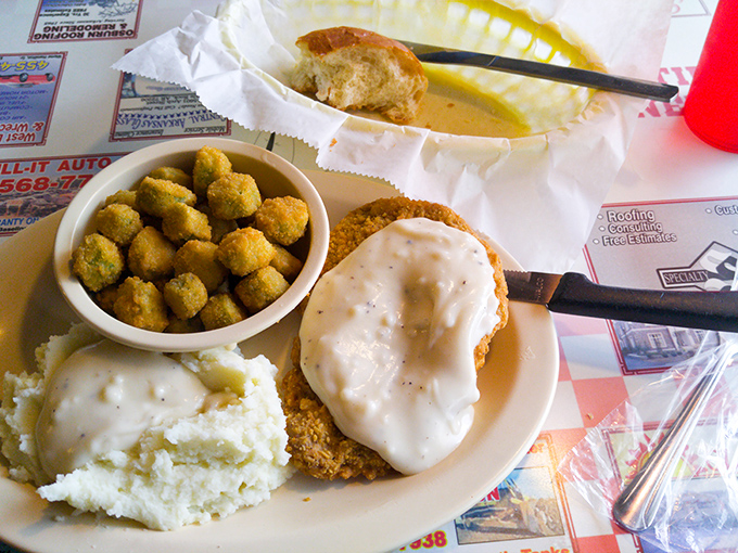 Southern comfort on a plate—chicken fried steak smothered in pepper gravy alongside creamy mashed potatoes and fried okra that tastes like a warm Arkansas hug. 