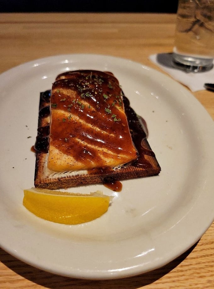 Cedar-planked salmon that's been kissed by flame and glazed to perfection. The lemon wedge isn't garnish—it's the exclamation point on a delicious sentence.