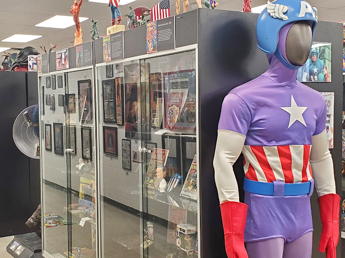 The vintage Captain America poster beside his iconic shield reminds us that before CGI and blockbuster budgets, heroes were born from simple ink and imagination.