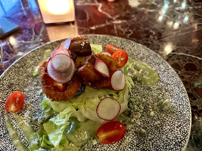 A wedge salad reimagined—crisp lettuce crowned with golden-fried delights and radish coins that add both crunch and visual pop.