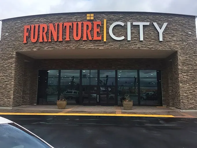 The grand entrance to Furniture City beckons with its impressive stone facade and bold signage—like the pearly gates of home decor heaven.
