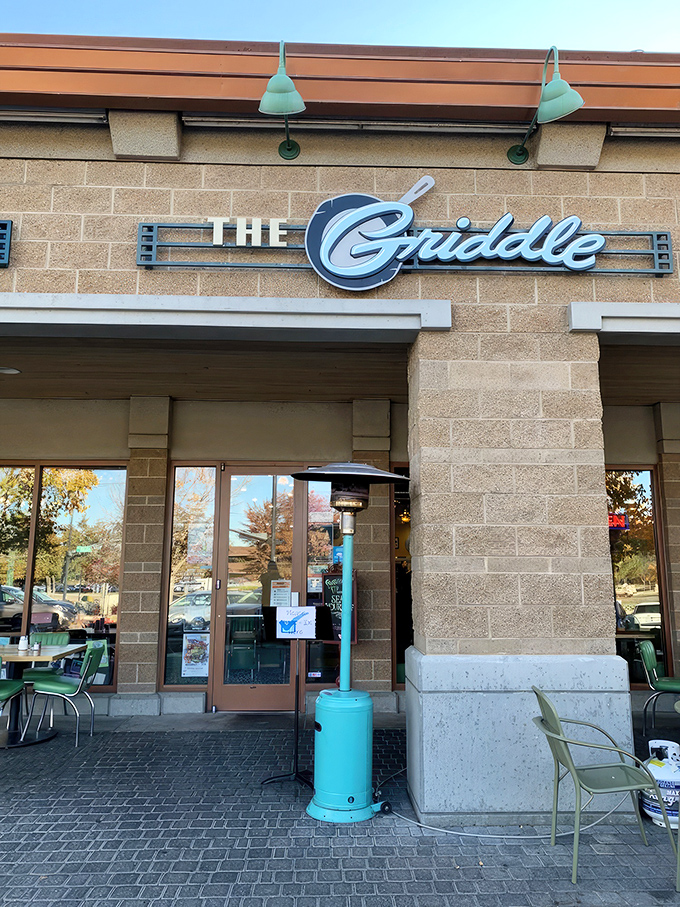 The stylish exterior of The Griddle beckons with its warm stone facade and signature blue lamps—breakfast paradise hiding in plain sight.