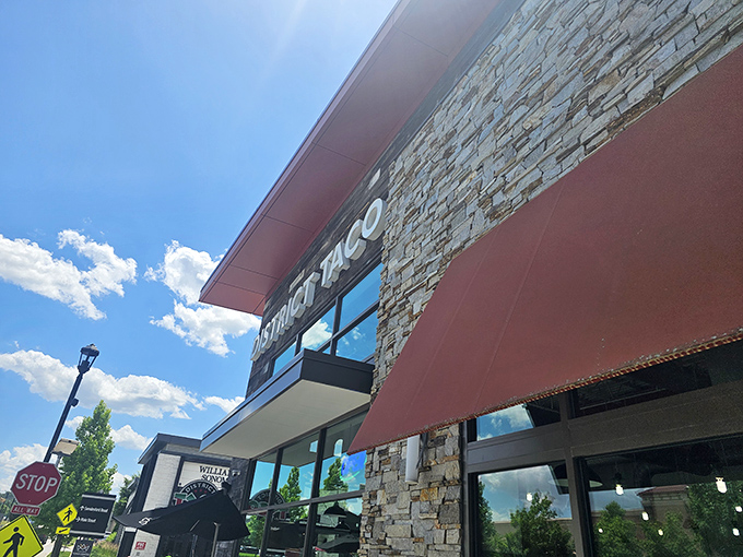 The rustic wooden exterior of District Taco welcomes hungry visitors with its vibrant sign and colorful flower boxes—a taco oasis in King of Prussia.