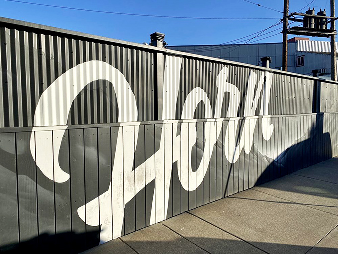 The unassuming exterior of Horn BBQ in Oakland – where that bold white lettering against dark panels is the architectural equivalent of a whisper about the best-kept secret in town.