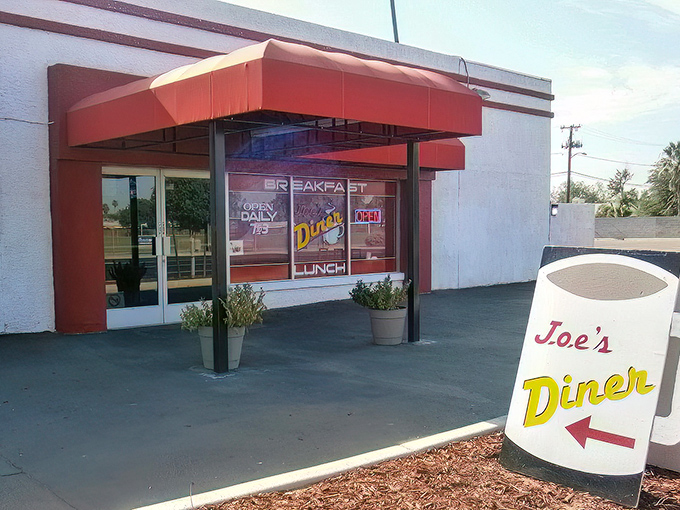 The unassuming yellow exterior of Joe's Diner stands like a beacon of breakfast hope in Phoenix, promising hash brown nirvana behind that green awning.