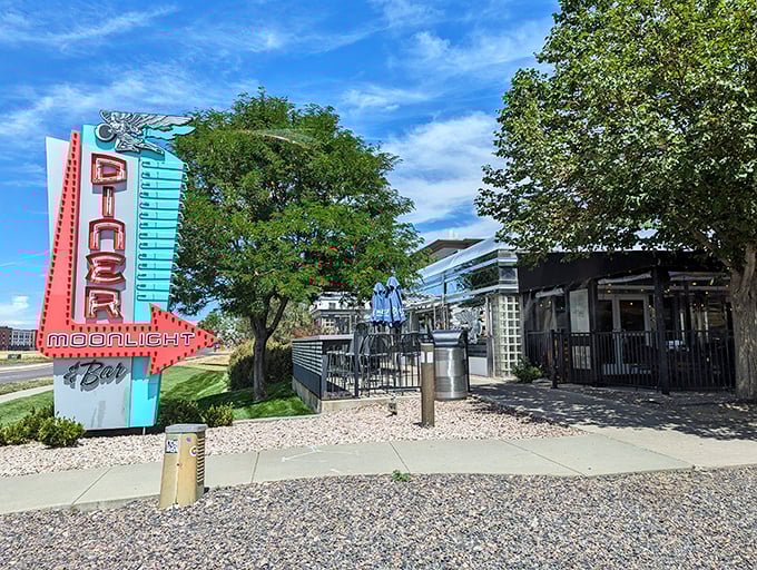 That neon sign doesn't whisper—it announces with retro swagger: "Hungry humans, your comfort food paradise awaits!" The turquoise and red color scheme practically sings against the Colorado sky.
