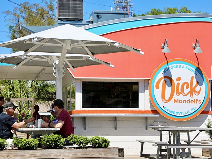 The bright orange and turquoise exterior isn't just eye-catching—it's a siren call to burger lovers everywhere. Florida sunshine and shade umbrellas complete the perfect dining setup.