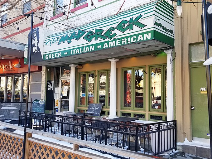 The Mad Greek's inviting storefront beckons with classic white columns and cheerful patio umbrellas—Massachusetts Street's little slice of Athens awaits your discovery.