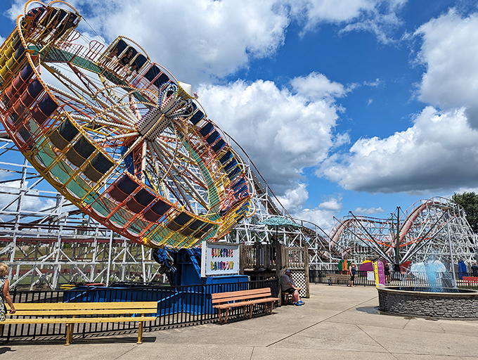 The classic Scrambler ride spins against a backdrop of wooden coaster tracks – a perfect snapshot of old-school amusement park magic that never goes out of style.