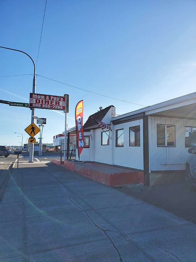 The classic red and white sign beckons like a lighthouse for hungry travelers. Mom and Pop's Diner isn't just a place—it's a promise of comfort ahead.