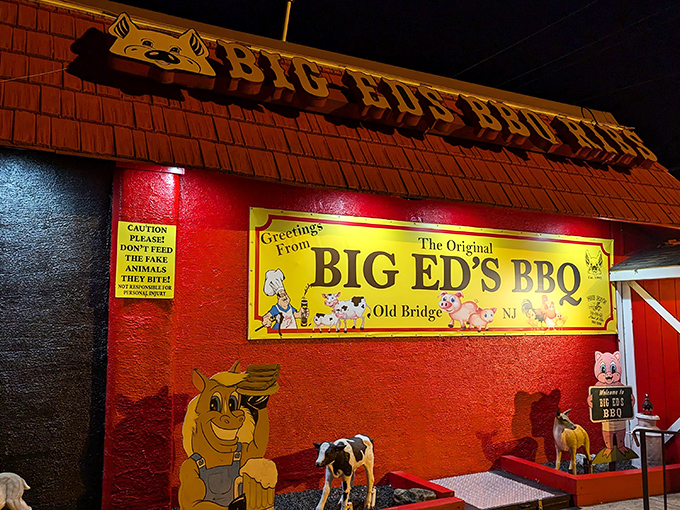 The barn-red exterior of Big Ed's BBQ stands out like a beacon for hungry travelers, complete with whimsical pig and cow cartoons that promise delicious things inside.
