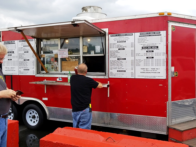 The bright red food truck stands like a culinary lighthouse in the parking lot, beckoning hungry souls with promises of smoky delights.