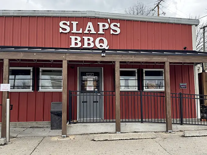 The iconic red exterior of Slap's BBQ stands as a beacon of hope for hungry pilgrims seeking smoky salvation in Kansas City's competitive barbecue landscape.