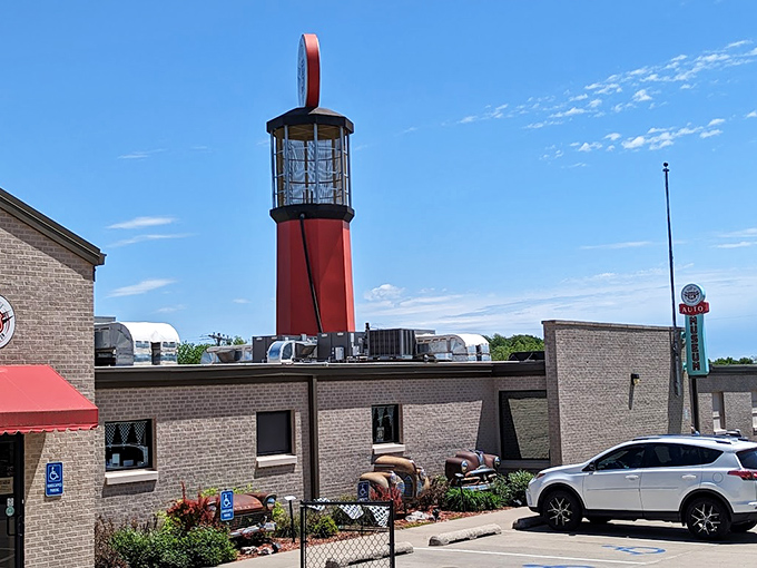 The museum's exterior features a striking lighthouse-style gas pump tower and vintage car parts artfully incorporated into the landscaping—automotive archaeology at its finest!