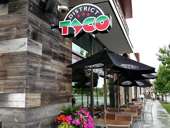 The rustic wooden exterior of District Taco welcomes hungry visitors with its vibrant sign and colorful flower boxes—a taco oasis in King of Prussia.