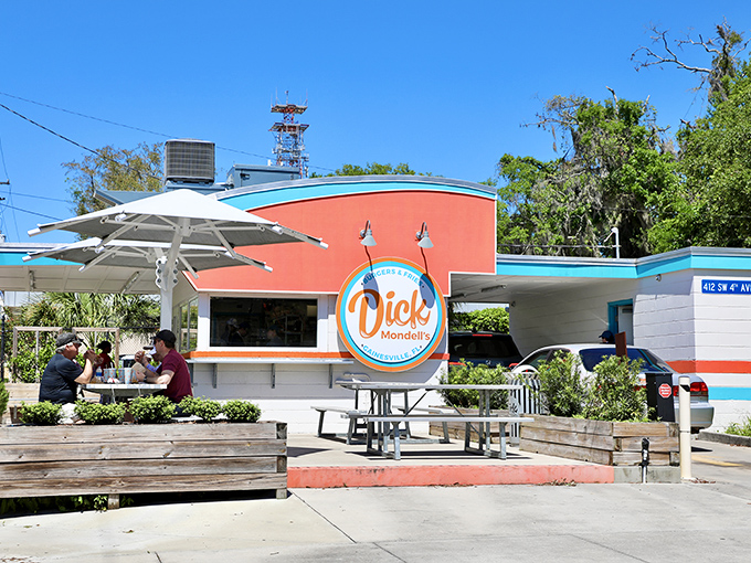 The bright orange and turquoise exterior isn't just eye-catching—it's a siren call to burger lovers everywhere. Florida sunshine and shade umbrellas complete the perfect dining setup.