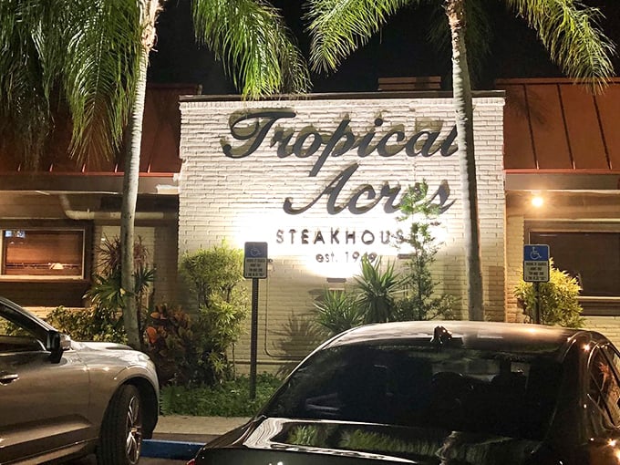 The iconic white brick façade of Tropical Acres glows invitingly at night, palm trees standing guard like old friends welcoming you home.