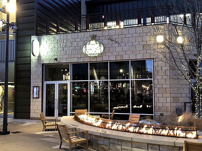 The Brass Onion's inviting exterior glows at twilight, with a cozy fire feature that practically whispers, "Come in and stay awhile."
