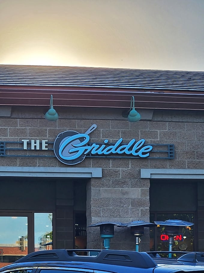 The stylish exterior of The Griddle beckons with its warm stone facade and signature blue lamps—breakfast paradise hiding in plain sight.