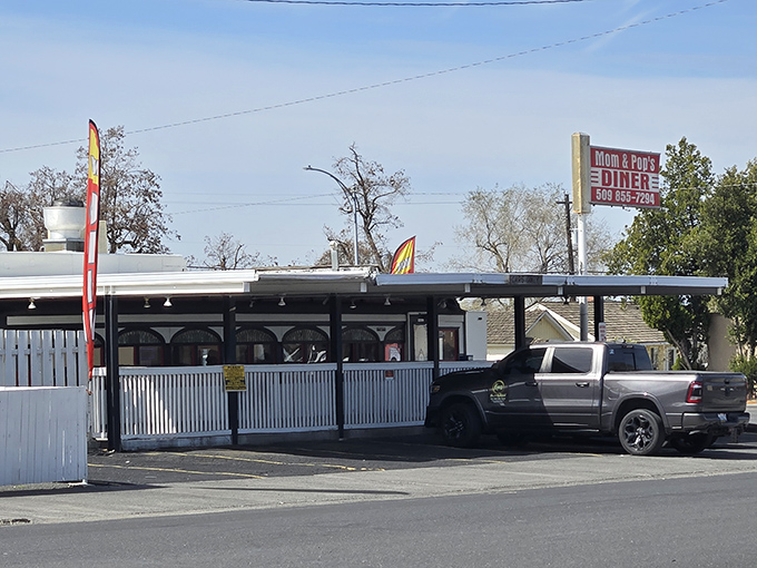 The classic red and white sign beckons like a lighthouse for hungry travelers. Mom and Pop's Diner isn't just a place—it's a promise of comfort ahead.