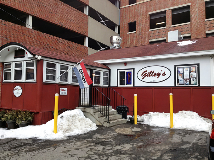 A humble red and white diner nestled against a parking garage—proof that culinary treasures often hide in plain sight.