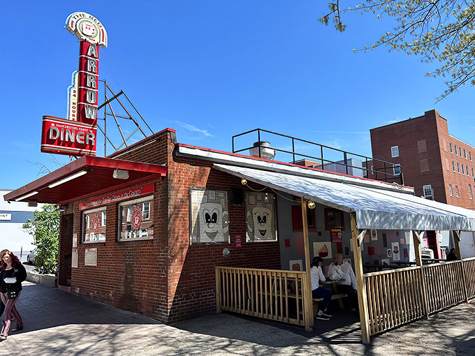 The iconic Red Arrow Diner sign beckons hungry travelers like a neon lighthouse in a sea of Manchester brick. Classic Americana at its finest.