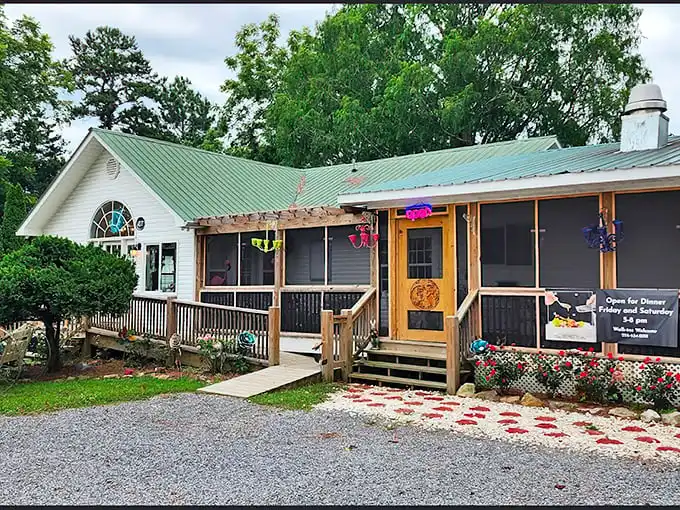 A storybook cottage nestled among towering trees, The Hatter Café's charming exterior promises whimsical adventures before you even step inside.