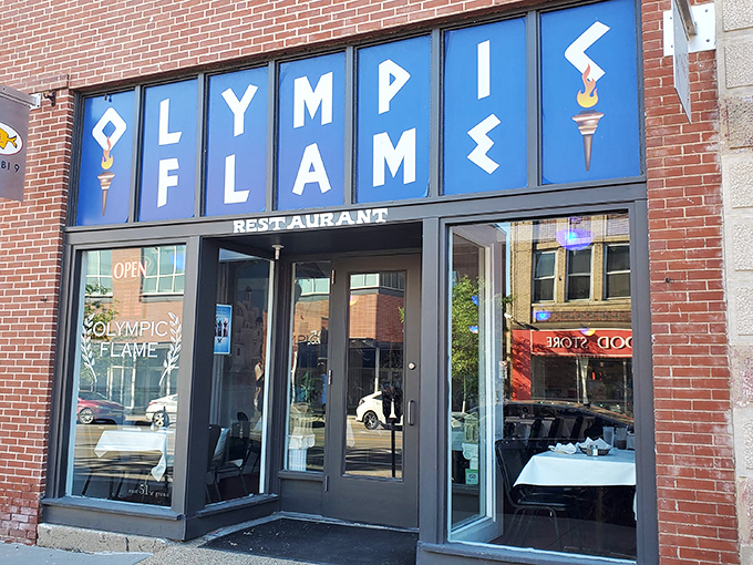 The blue signage of Olympic Flame beckons like a Mediterranean lighthouse amid Des Moines' brick buildings. Greek cuisine awaits!
