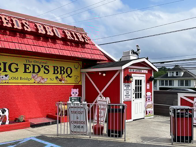 The barn-red exterior of Big Ed's BBQ stands out like a beacon for hungry travelers, complete with whimsical pig and cow cartoons that promise delicious things inside.