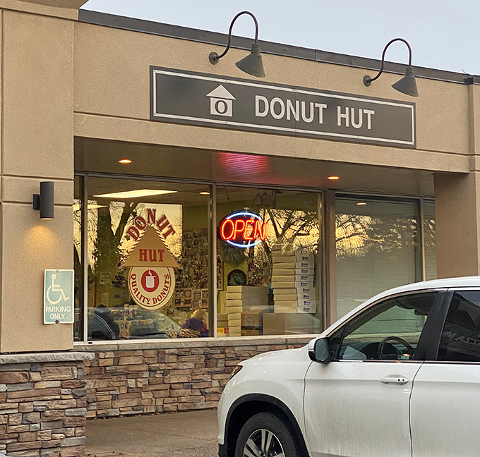 The humble storefront belies the sugary treasures within. Donut Hut's glowing "OPEN" sign serves as a beacon for pastry pilgrims across the Twin Cities.