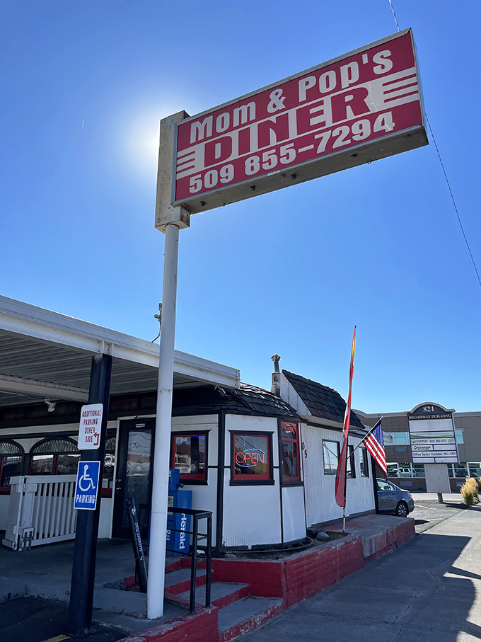 The classic red and white sign beckons like a lighthouse for hungry travelers. Mom and Pop's Diner isn't just a place—it's a promise of comfort ahead.