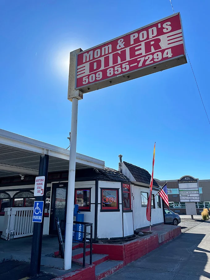 The classic red and white sign beckons like a lighthouse for hungry travelers. Mom and Pop's Diner isn't just a place—it's a promise of comfort ahead.