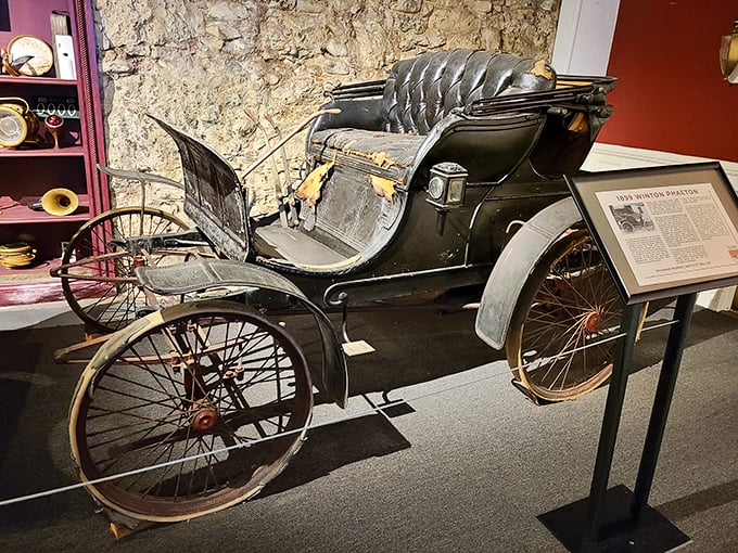 The 1899 Winton Phaeton looks more like a horseless carriage than a car, with its primitive controls and open design—the Model T's great-grandfather.
