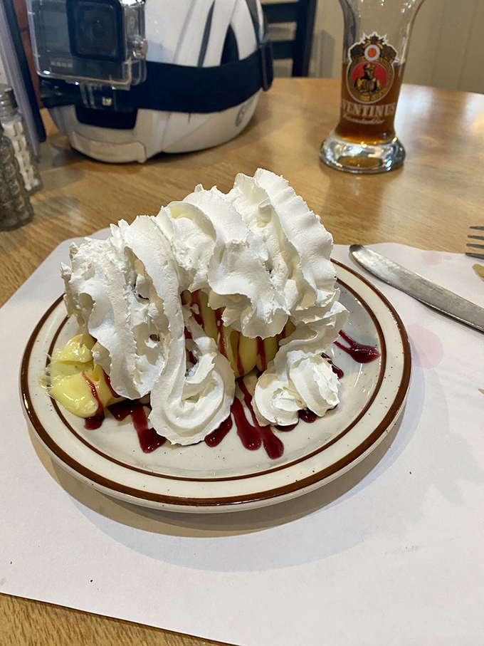 Whipped cream mountains atop what appears to be cheesecake—a dessert so excessive it requires both a fork and a climbing permit.