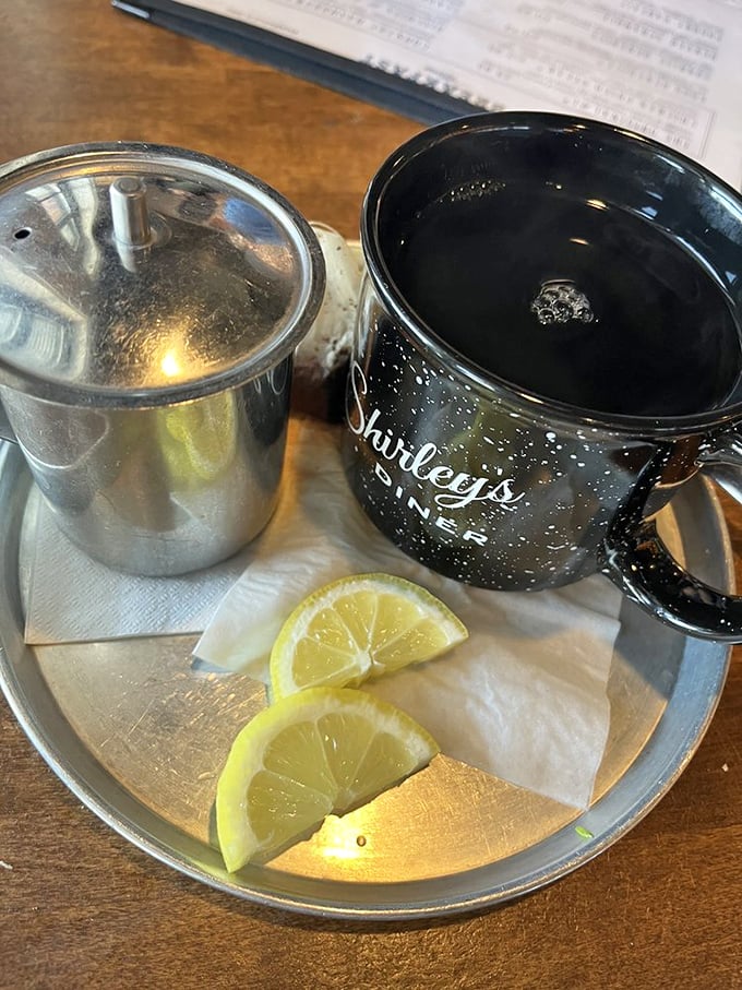 A proper cup of hot tea served with lemon wedges and a small metal pot for refills – civilization in a ceramic mug.