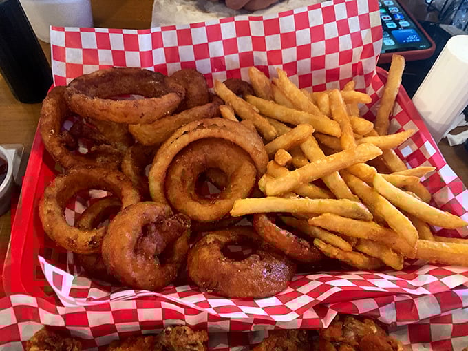 Onion rings and fries coexisting peacefully on red-checkered paper—proof that different shapes of fried goodness can share the spotlight gracefully.