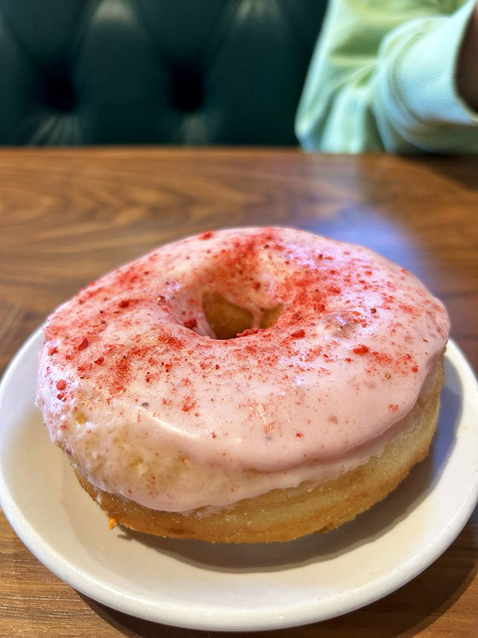 This isn't just a donut – it's a pink-frosted morning indulgence that somehow makes adulting seem completely optional for the day.