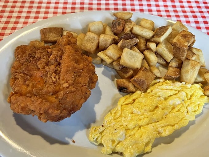 The holy trinity of Southern breakfast—crispy fried chicken, perfectly cooked eggs, and golden home fries that make waking up early seem like a brilliant idea.