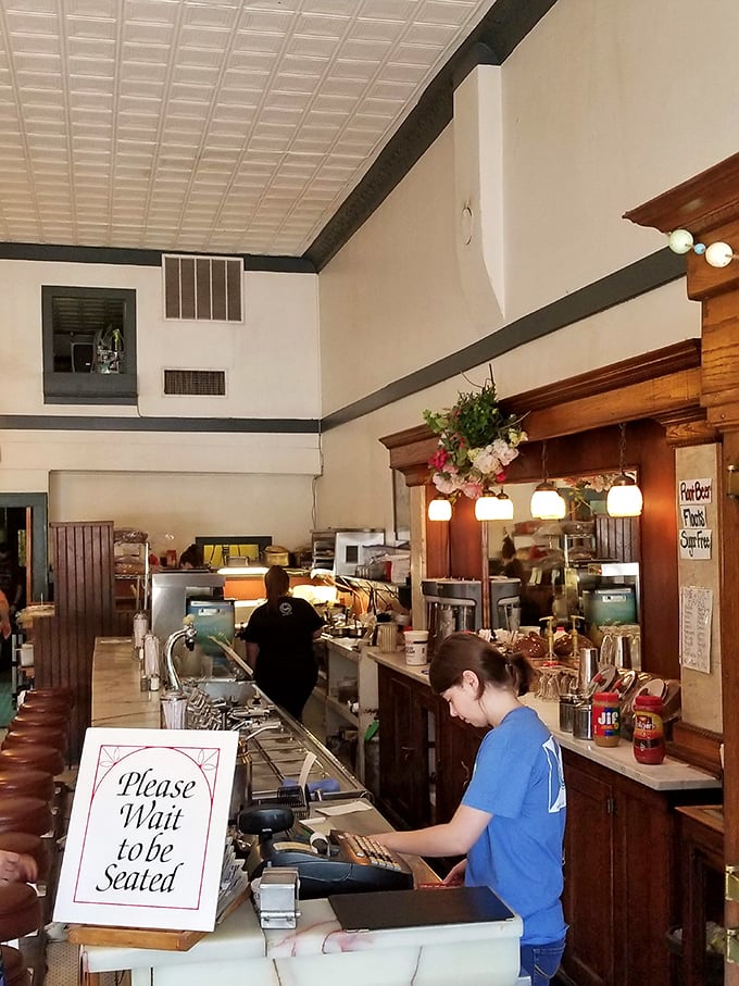 Please Wait to be Seated is just their polite way of saying "Prepare for a memorable experience." The soda fountain equipment stands ready for action.