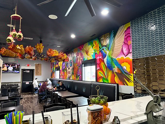 The vibrant mural featuring hummingbirds and flowers isn't just wall decor—it's a visual mariachi band serenading your meal with color.