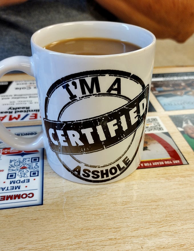 The coffee mug speaks the unvarnished truth—a perfect match for a diner where authenticity trumps pretense every time.