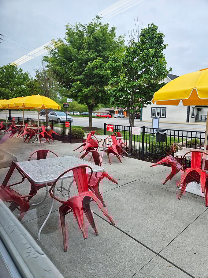The patio's cheerful red chairs and yellow umbrellas create an outdoor dining space that's sunnier than an optimist's outlook on Monday morning.