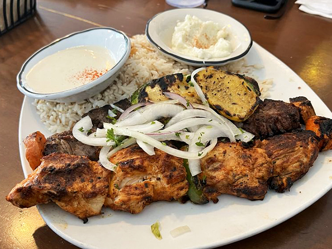 The holy trinity of Mediterranean meats. Chicken, lamb, and beef share the spotlight with grilled vegetables and rice—a plate that demands to be photographed.