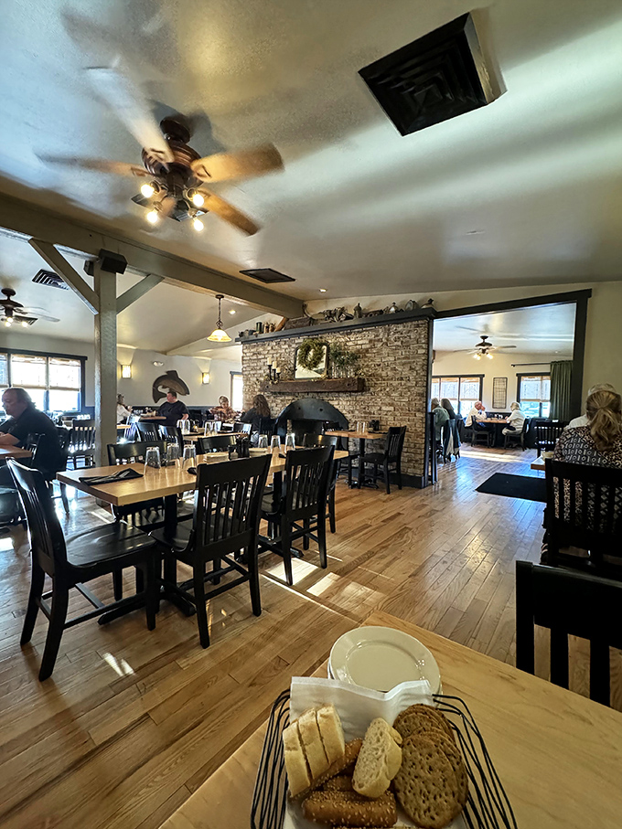 A dining room where memories are made – wooden floors, stone fireplace, and tables filled with people who understand that good food is worth the drive.