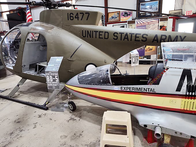 Military meets experimental as these aircraft share hangar space like odd roommates. The Army helicopter seems to be keeping a watchful eye on its civilian neighbor.