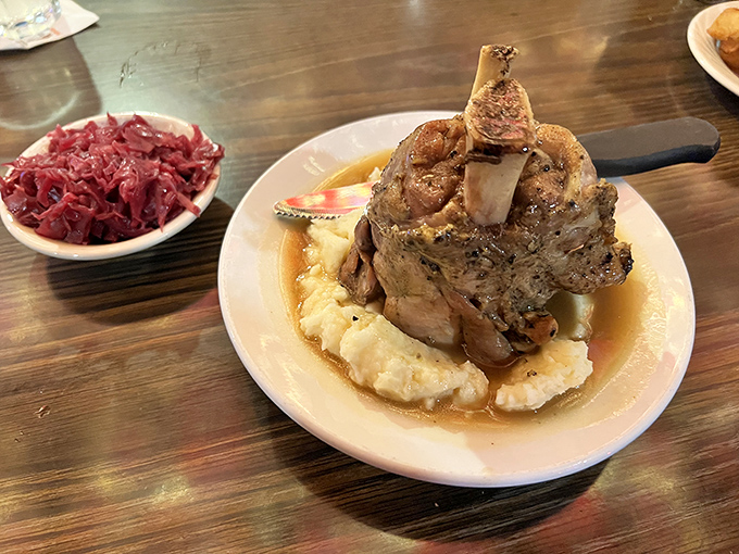 This isn't just a pork shank—it's a monument to meat, proudly standing in a pool of gravy with red cabbage as its loyal sidekick. Fork and knife required.