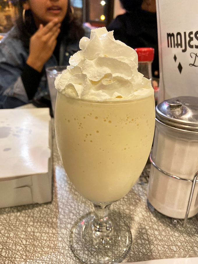This vanilla milkshake isn't just a drink—it's dessert masquerading as a beverage, with whipped cream playing the role of a jaunty hat.