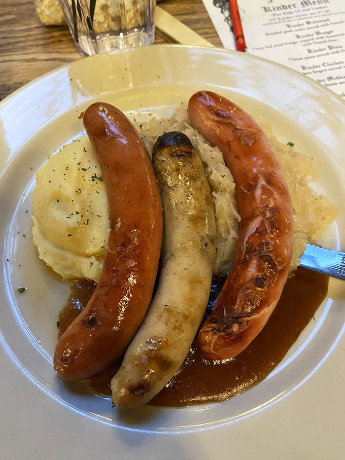 Three sausages standing at attention on a bed of mashed potatoes—a meaty tribute to German engineering and flavor architecture.